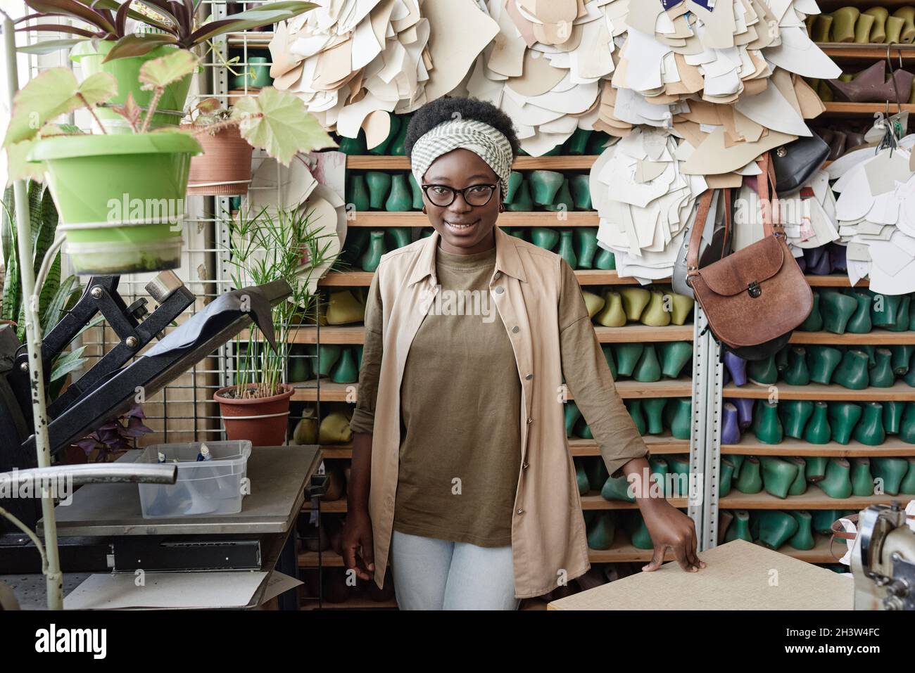 Portrait of African young shoemaker smiling at camera while standing in ...