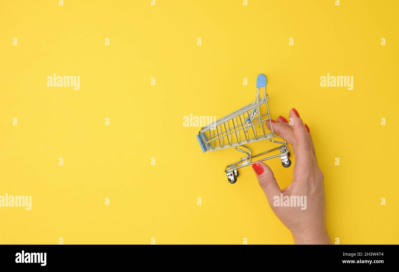 Grubby hands hold an empty metal miniature trolley on a yellow ...