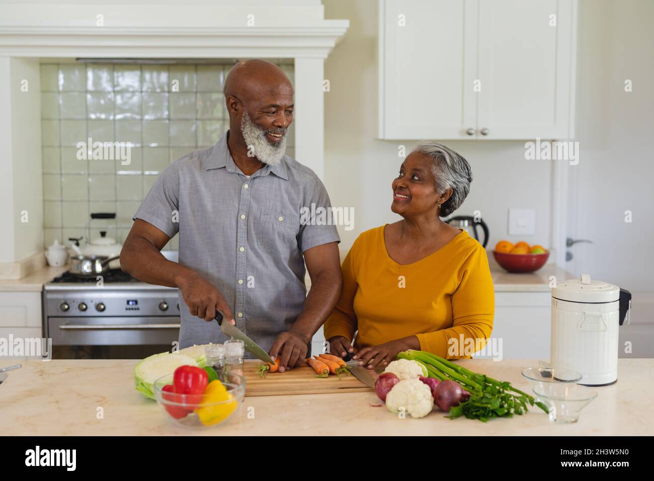 Senior african american couple cooking together in kitchen smiling ...