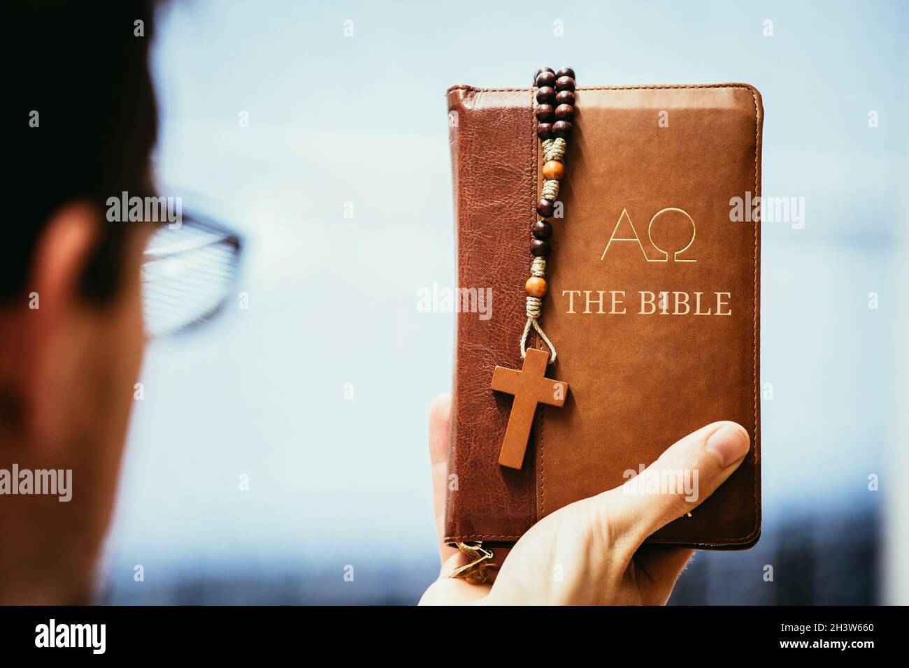 Christian preacher: Young man is holding the bible, praying Stock Photo ...