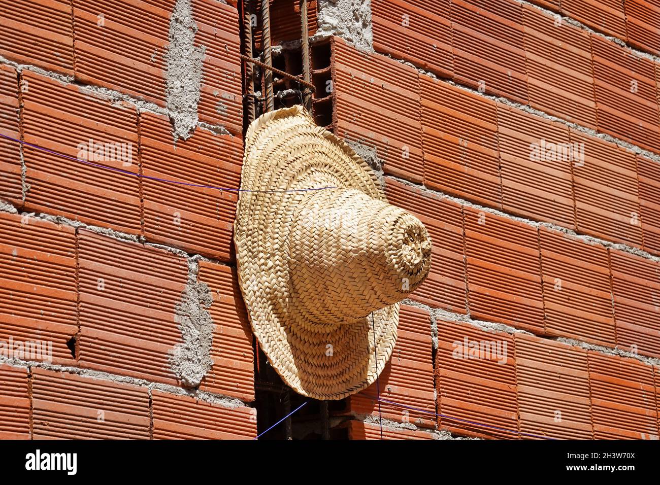Thatch hat hanging on the brick wall Stock Photo - Alamy