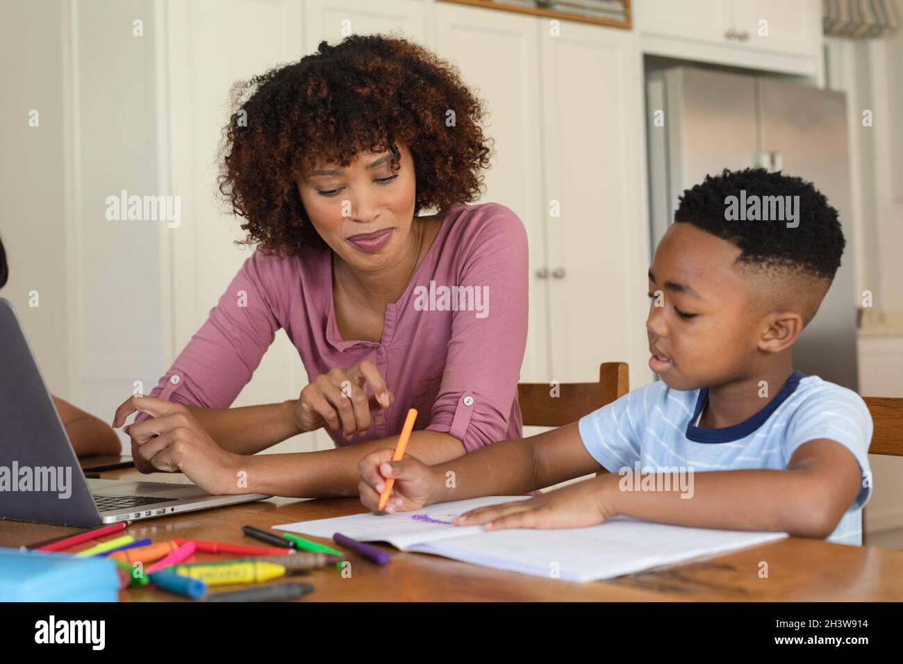 Happy african american mother and son doing homework at home smiling ...