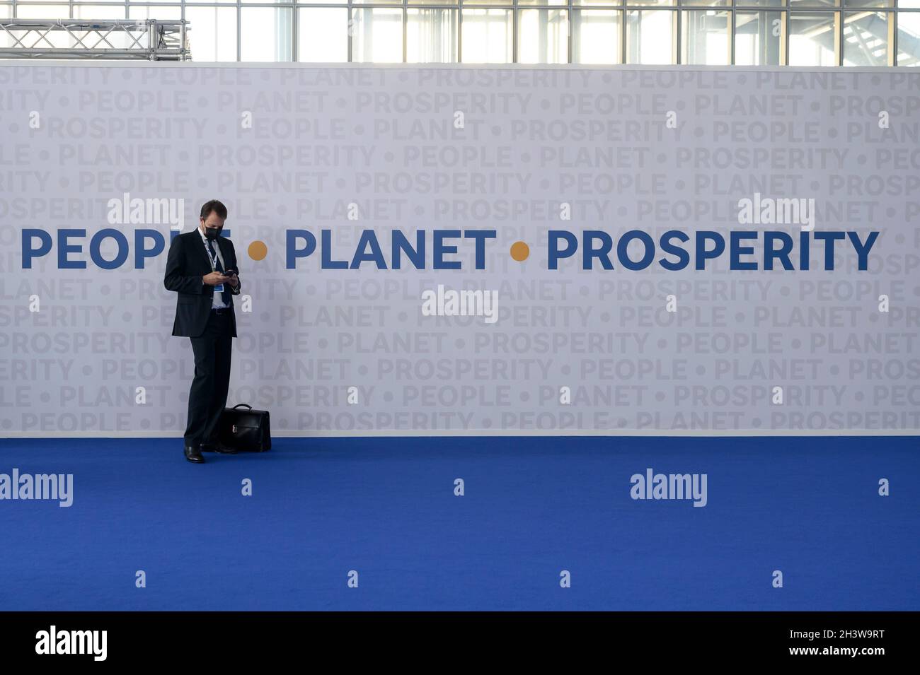 A man stands next to the motto of the G20 3 P "people, planet ...