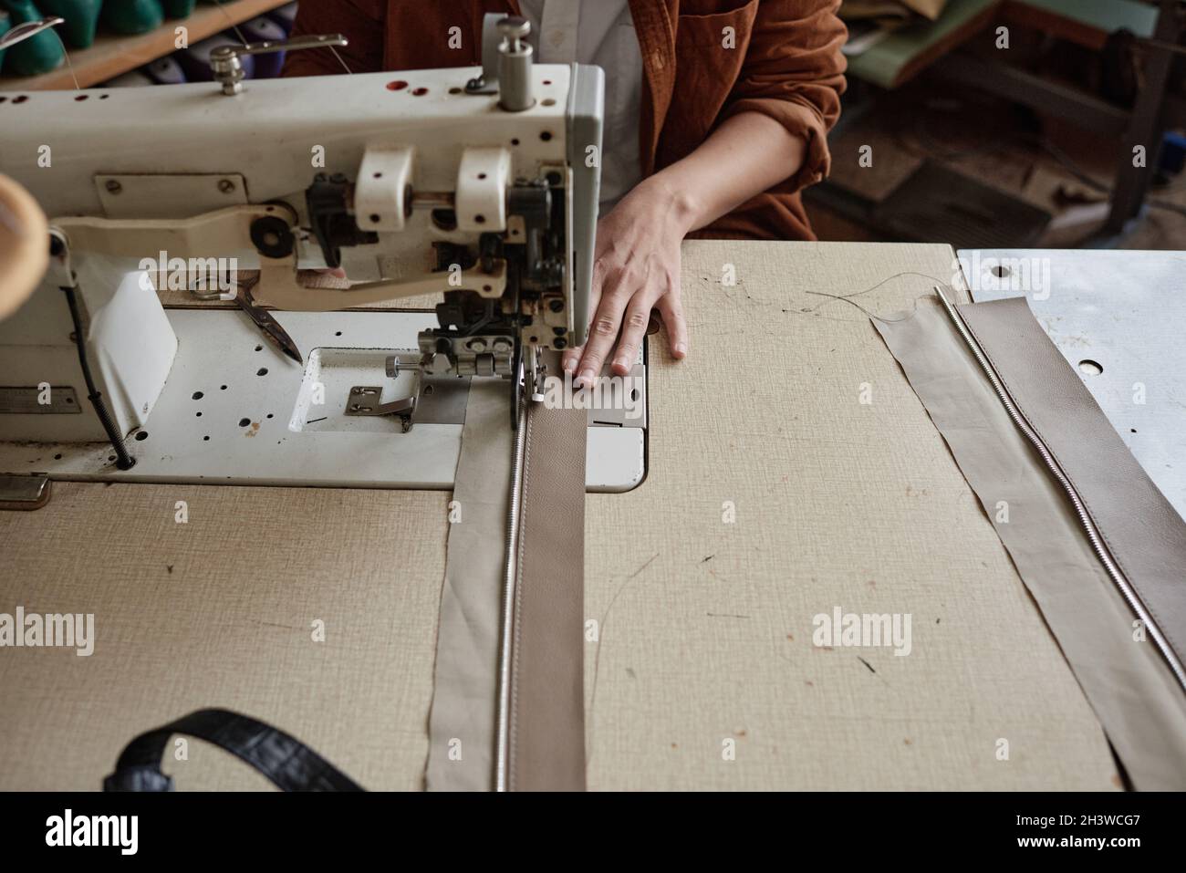 Close-up of female fashion designer working on sewing machine creating ...