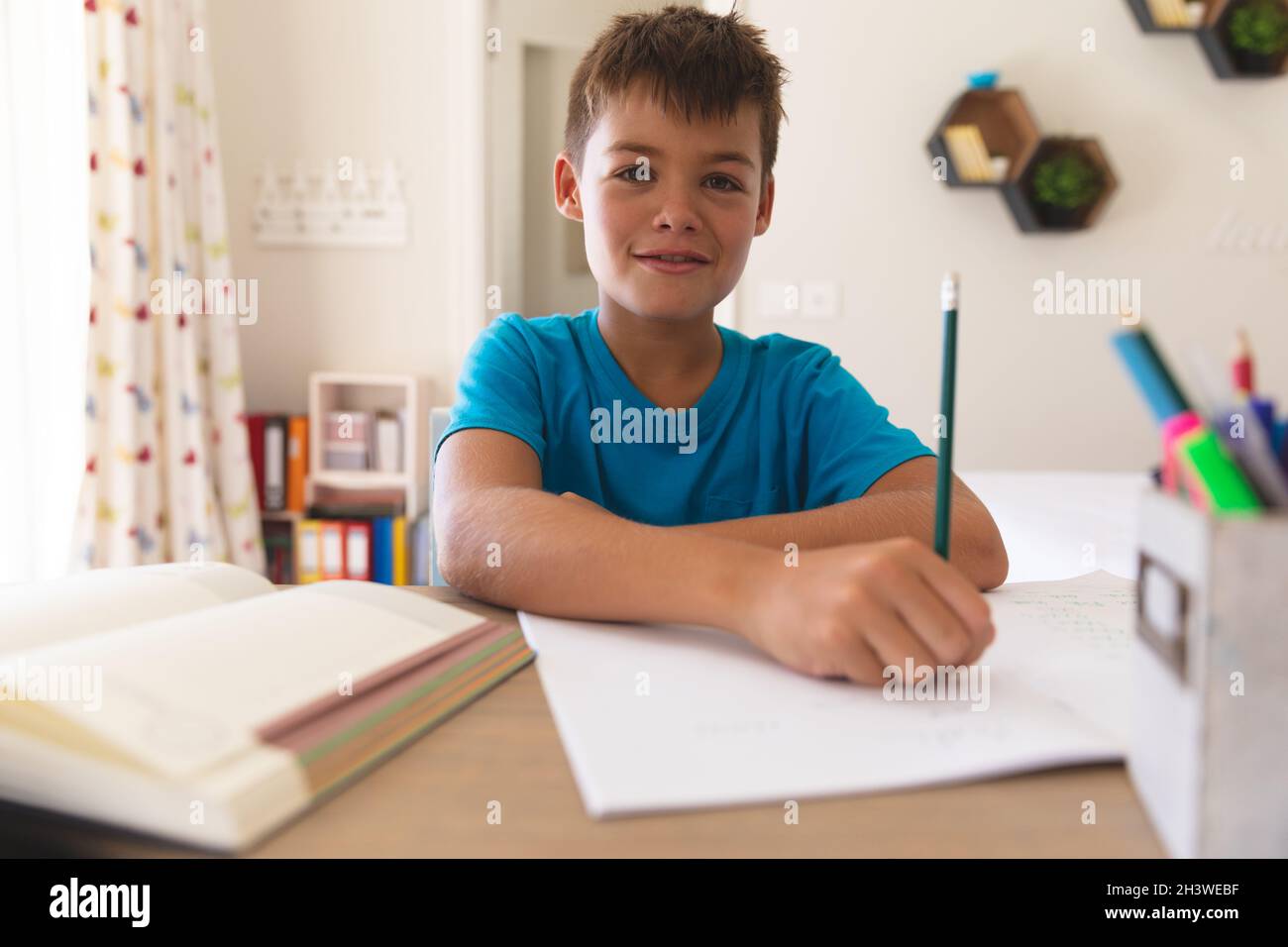 Smiling caucasian boy having video call during class, sitting at desk ...