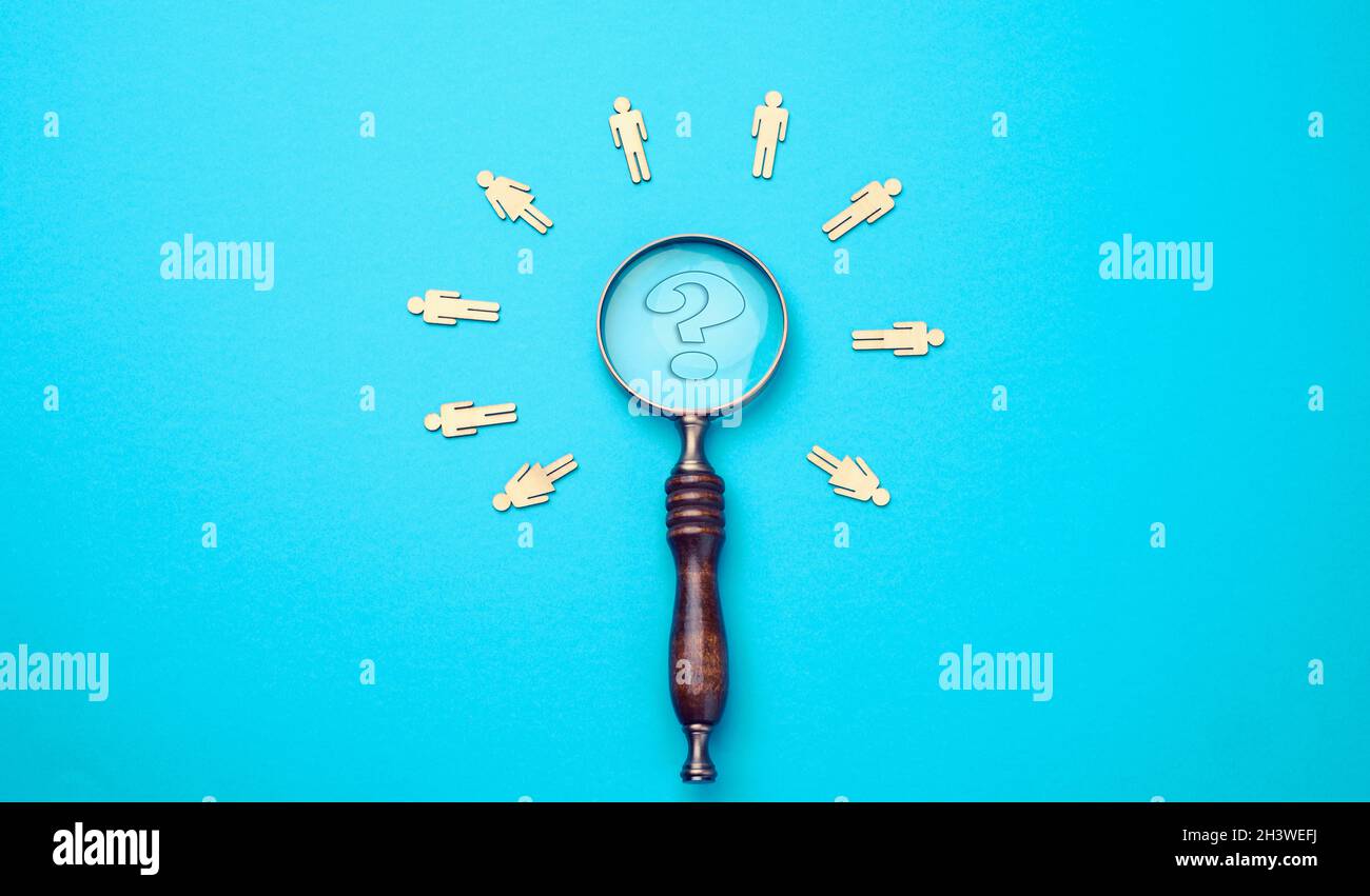 Wooden men and vintage magnifying glass on a blue background ...