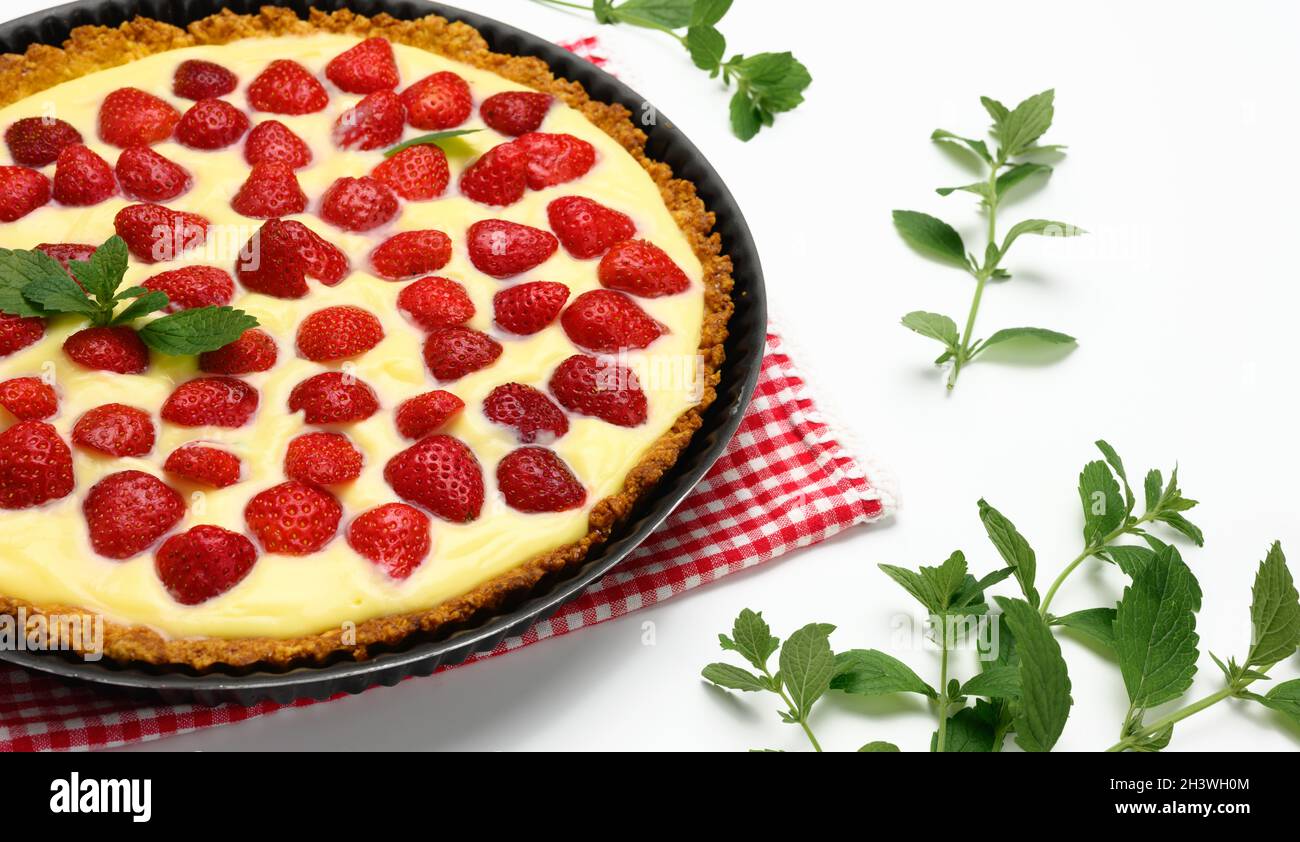 Baked round tart with strawberries and tender milk cream on a white ...
