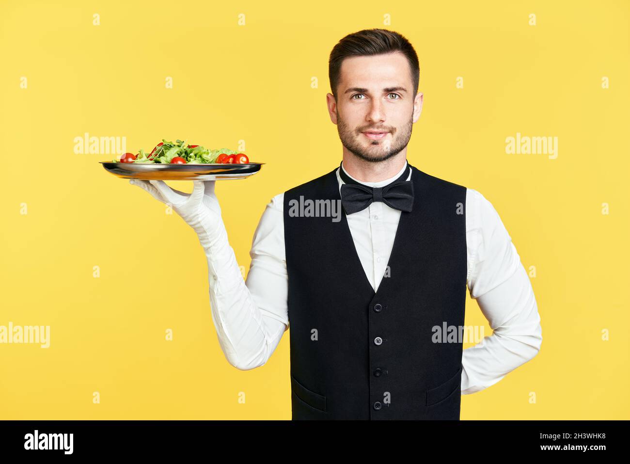 Happy smiling waiter holding plate with healthy vegetable salad ready ...