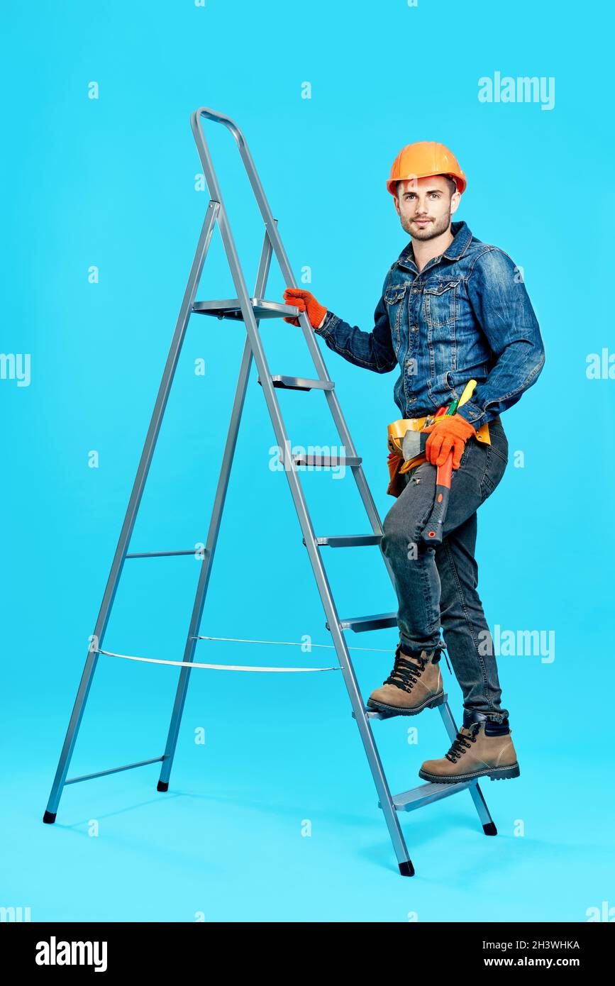 Full length portrait of handsome male construction worker climbing on ...