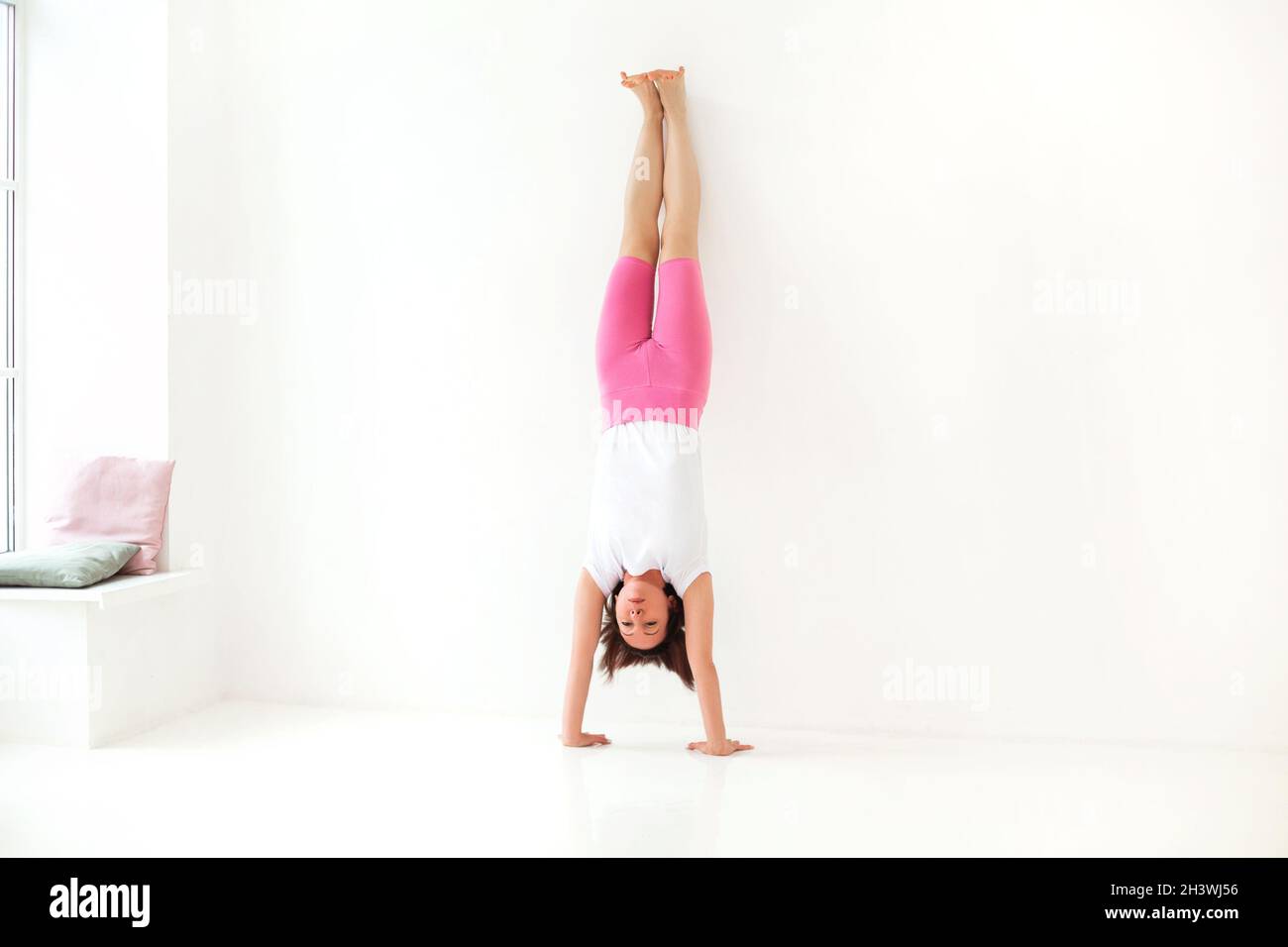 Slim woman doing balancing handstand asana Stock Photo - Alamy