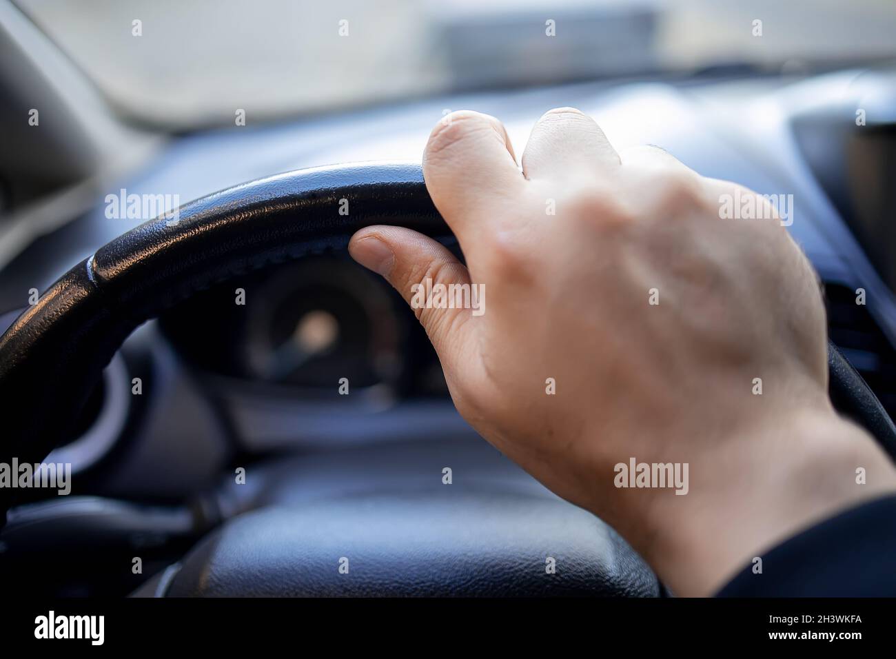 close-up of a man's hand holding the steering wheel of a car with two ...