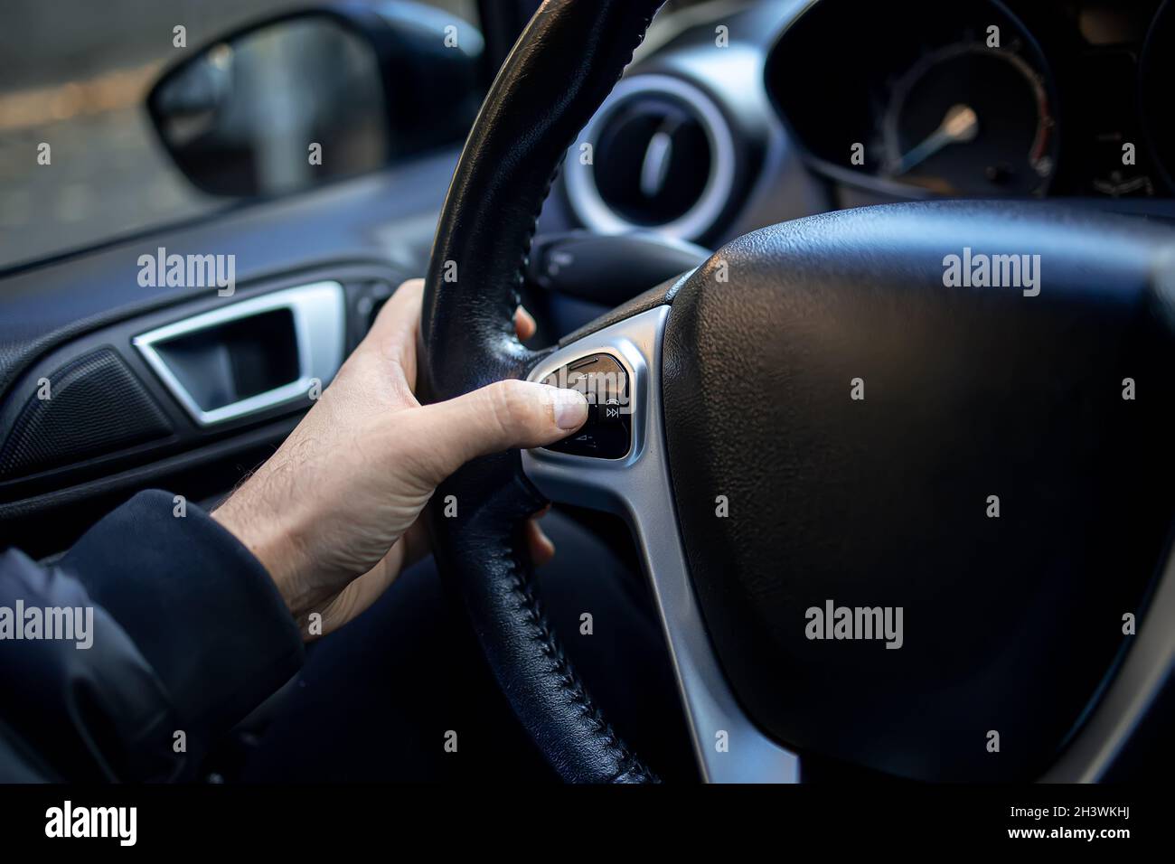 a man's hand holds the steering wheel of the car and controls the multi ...
