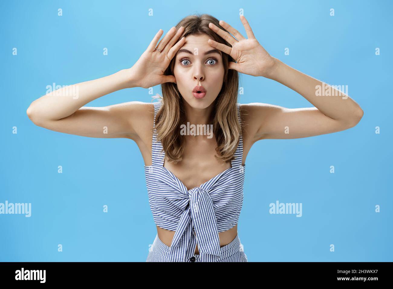 Woman looking surprised and impressed at camera after opening eyes ...