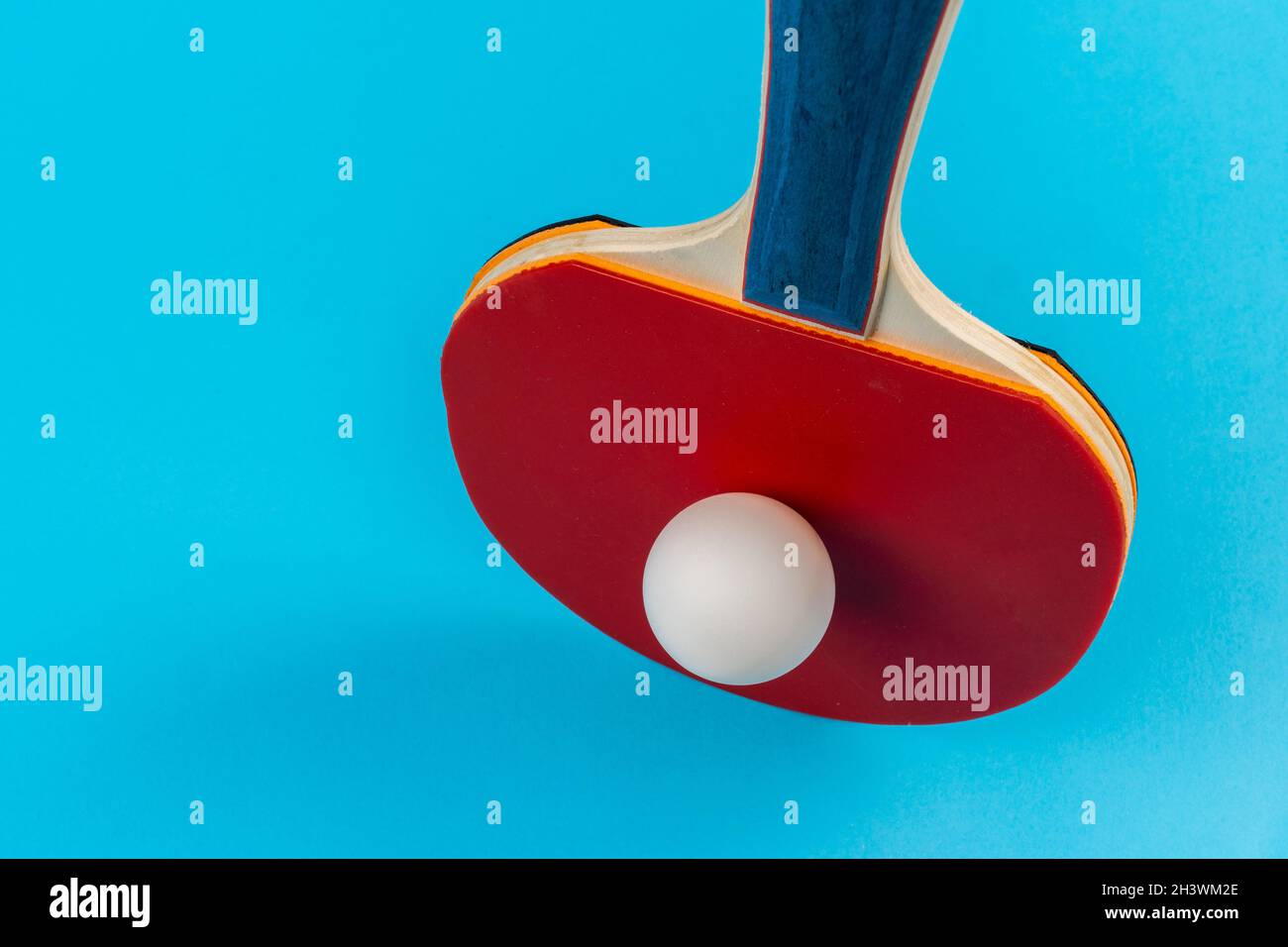 Red ping pong racket on a blue background Stock Photo - Alamy