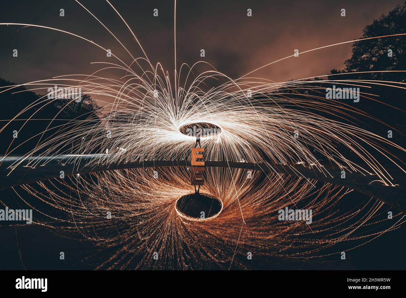 Man standing on an E letter near the pond and performing a fire show at ...