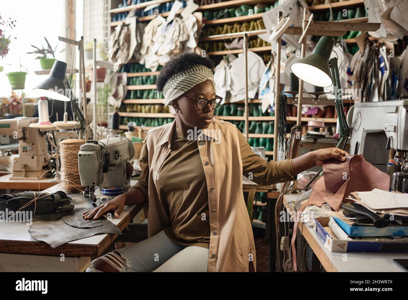 African tailor woman sitting at workplace with sewing machine taking ...
