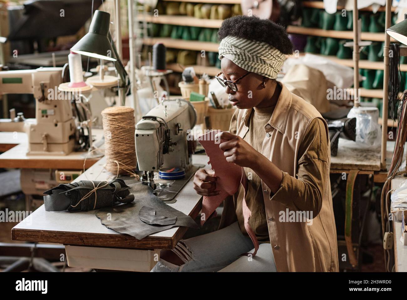 African seamstress sewing two pieces of fabric together on sewing ...