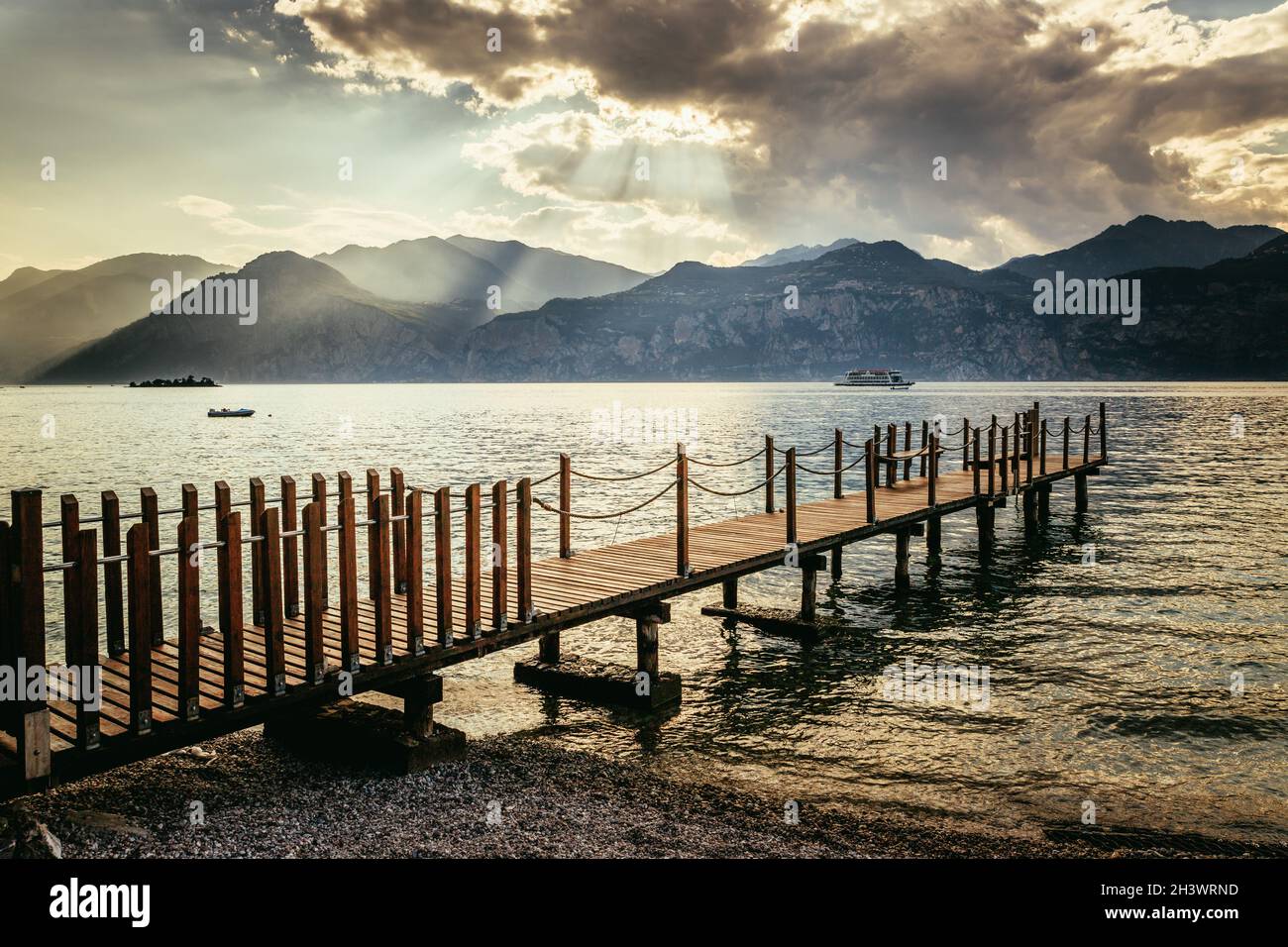 Summer holiday: Wooden dock pier over blue lake water. Cloudy evening ...