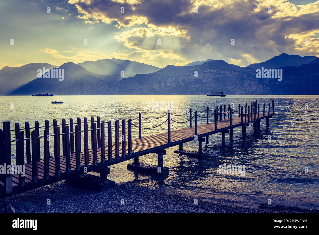 Summer holiday: Wooden dock pier over blue lake water. Cloudy evening ...