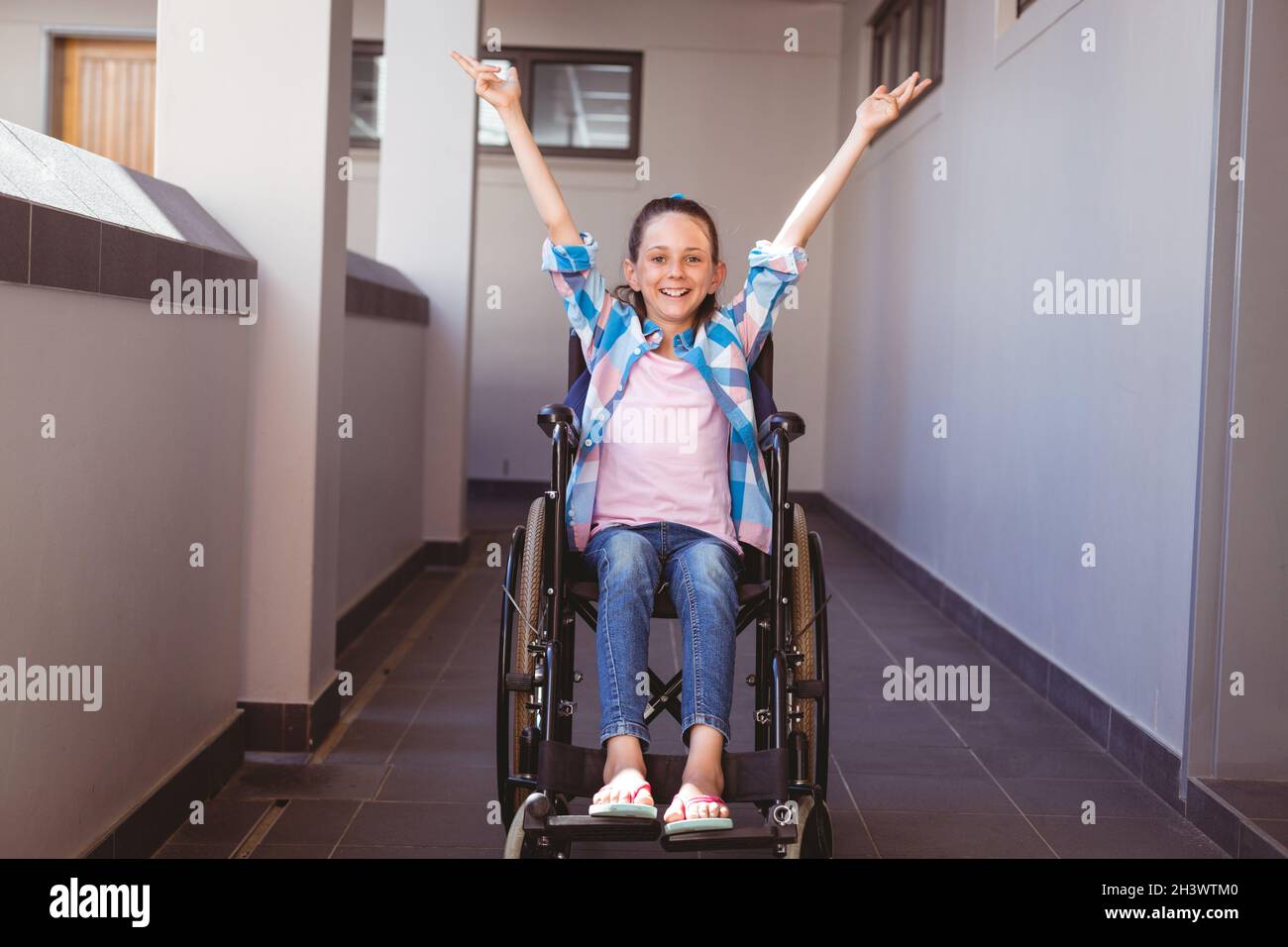 Portrait of smiling disabled caucasian schoolgirl sitting in wheelchair ...