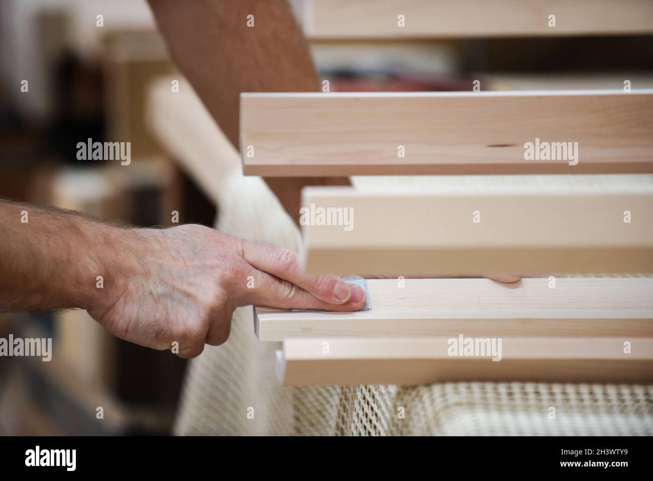 The man is sanding wood with sand paper in part of the furniture making ...