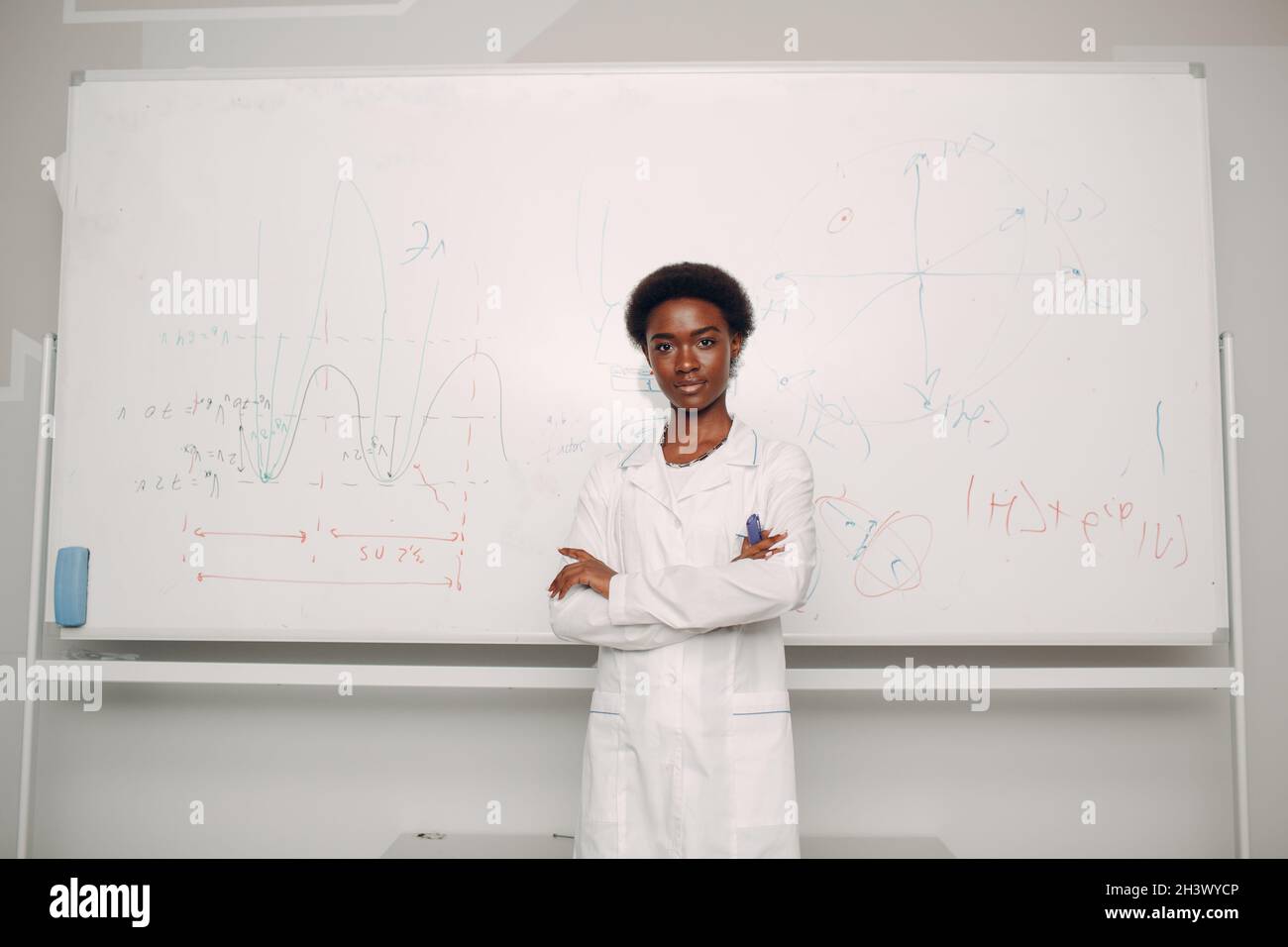 African American woman math teacher stands at blackboard with marker ...