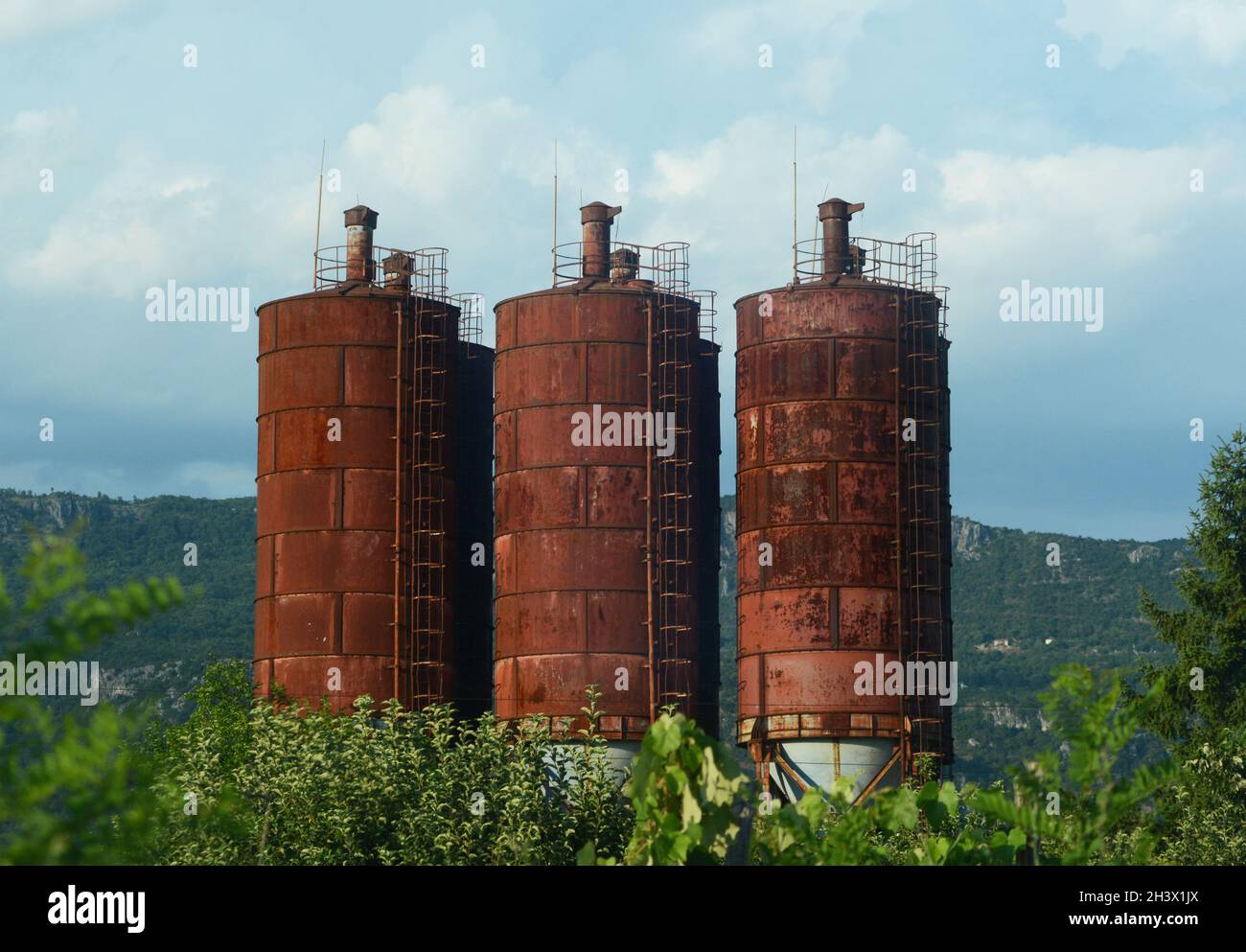 a three big rusty tanks with a blue sky with clouds in background Stock ...