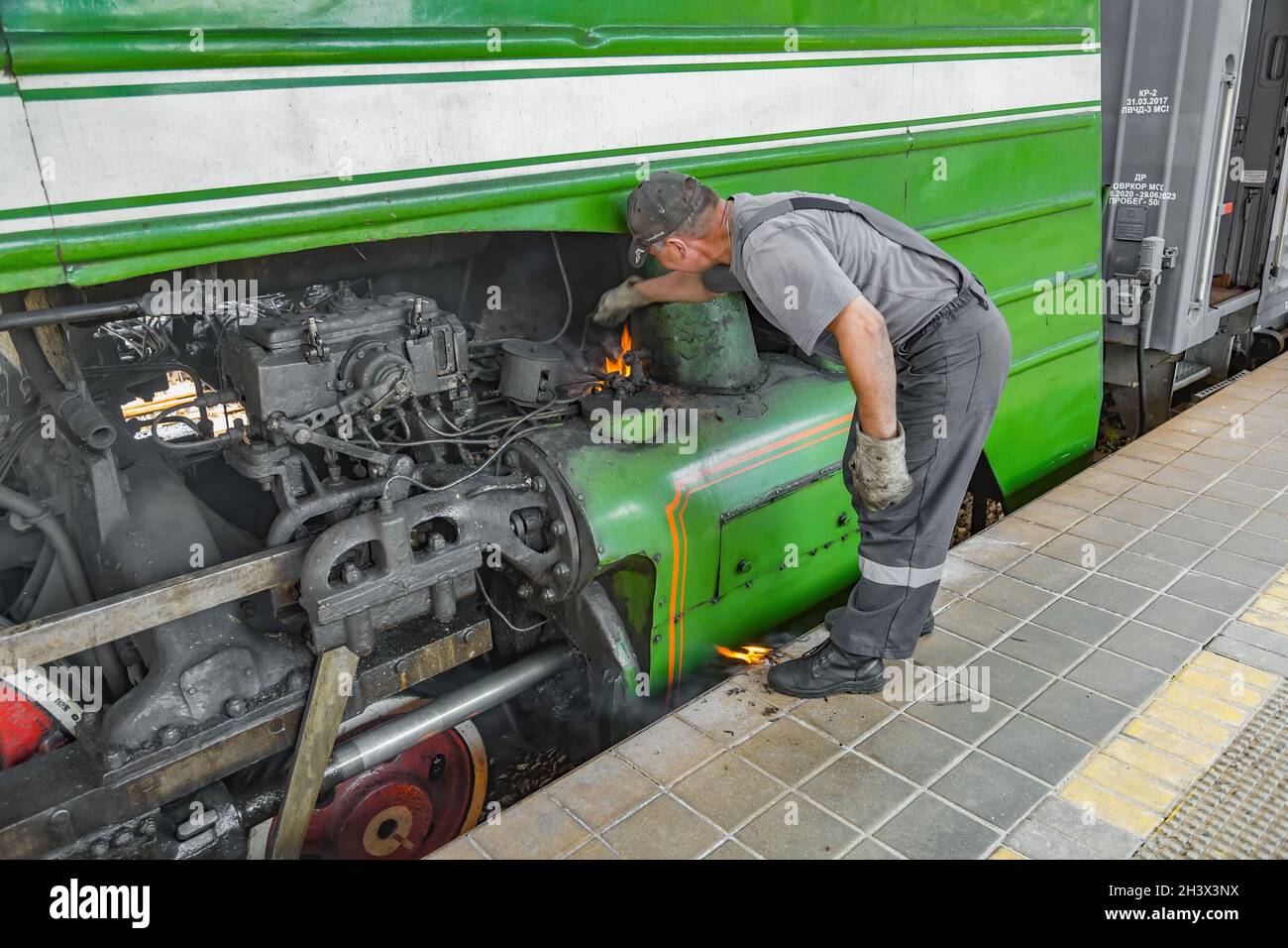 Worker extinguishes a retro steam locomotive on fire at railway station ...