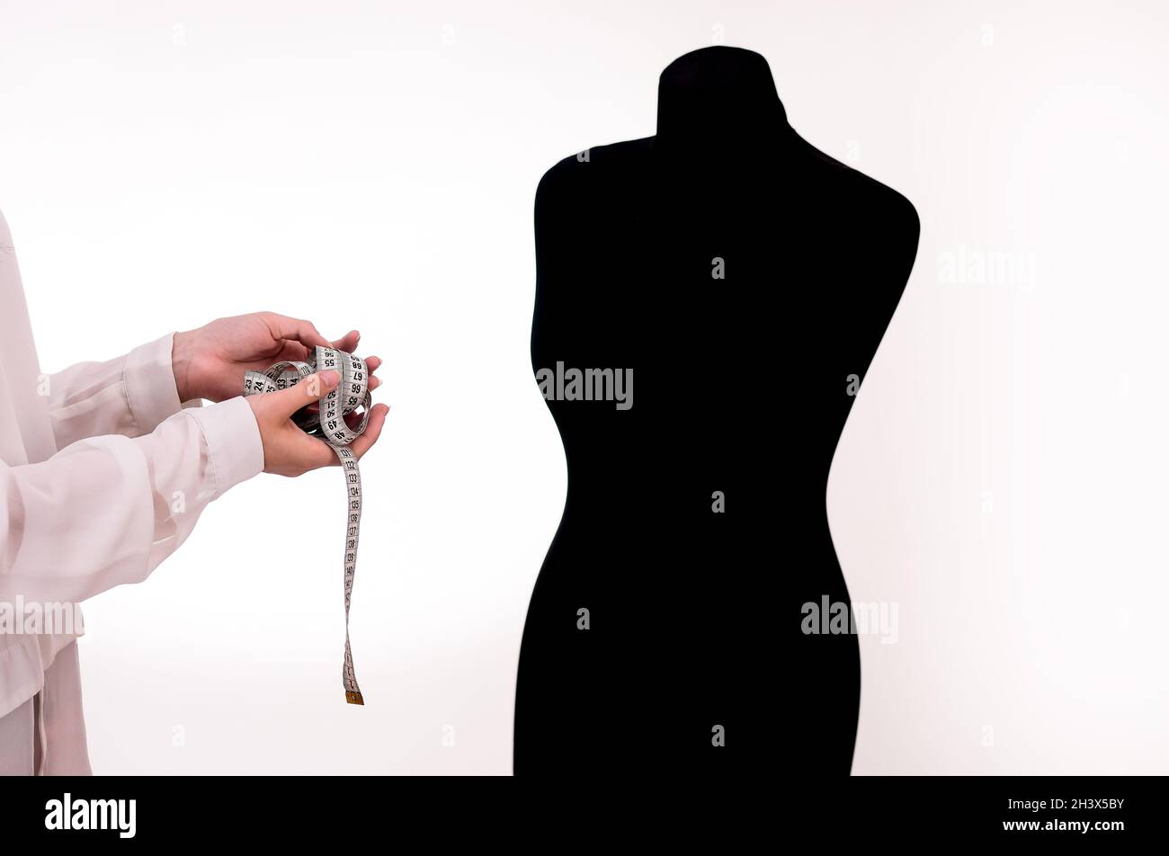 The seamstress's hands with a measuring ruler next to the mannequin ...