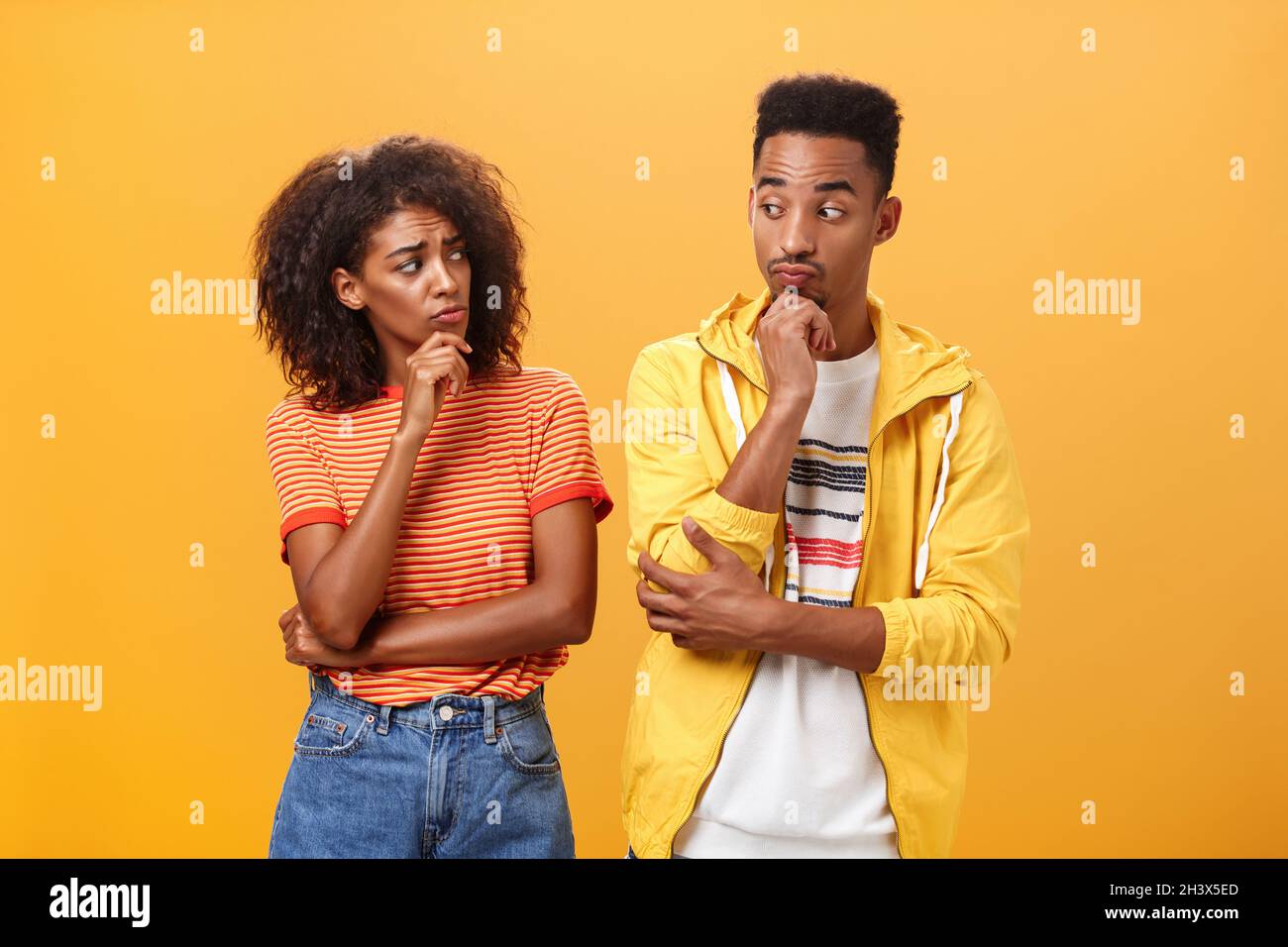 Silly confused girl standing gloomy and worried pursing lips and ...