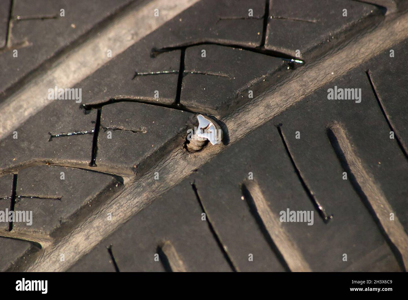 Punctured car wheel. Puncture of car wheel, steel screw is in tyre ...