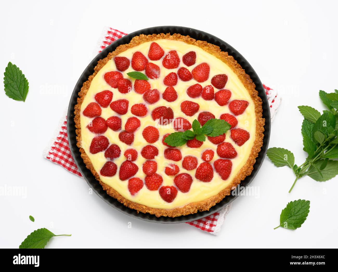 Baked round tart with strawberries and tender milk cream on a white ...