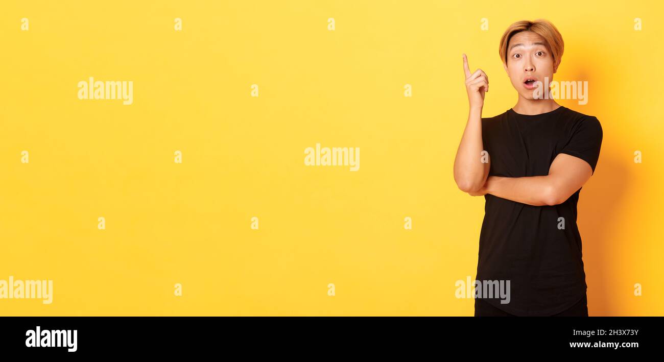 Portrait of thoughtful handsome asian man raising finger, suggesting ...