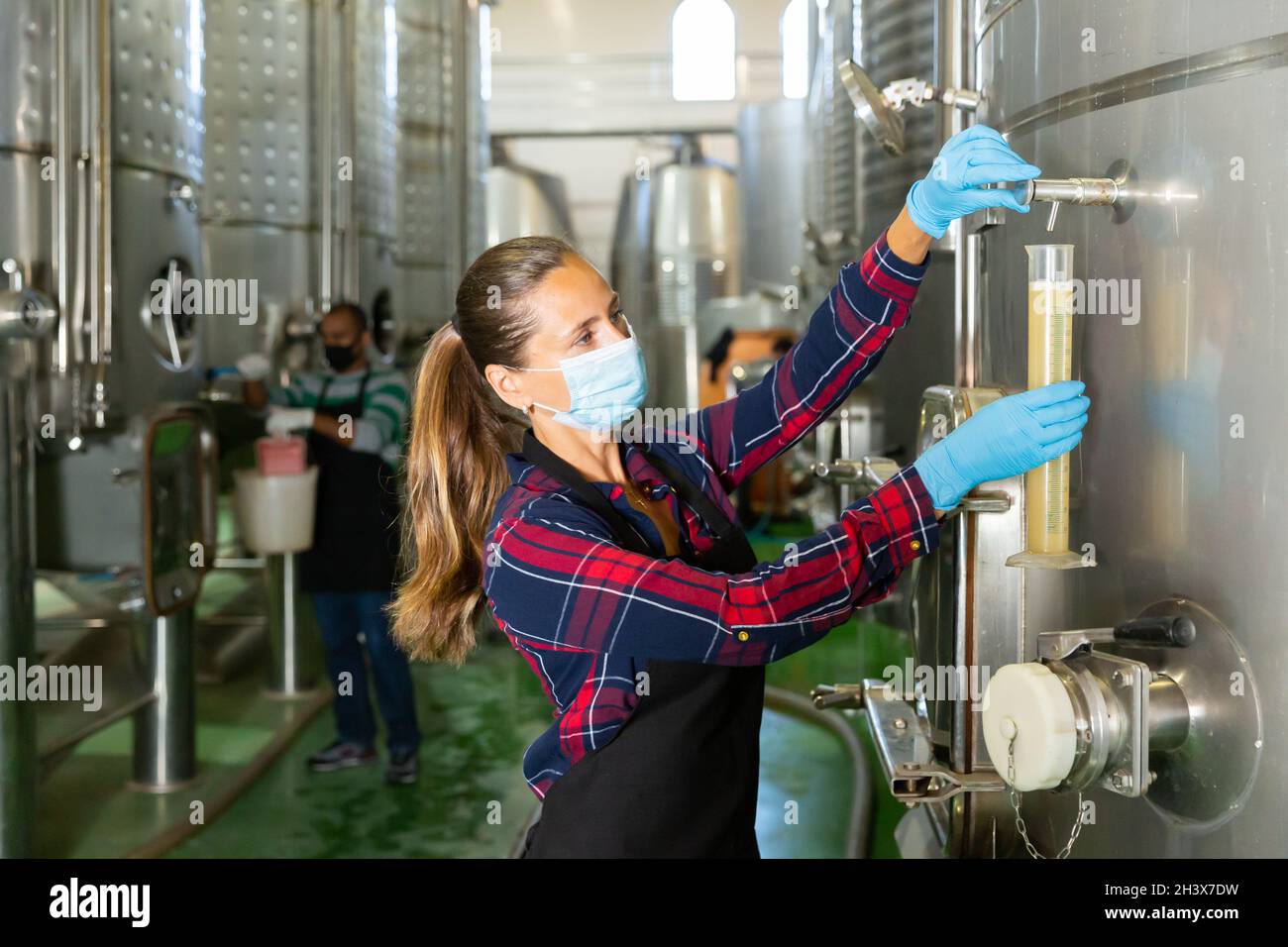 Woman vintner in mask checking wine process Stock Photo - Alamy