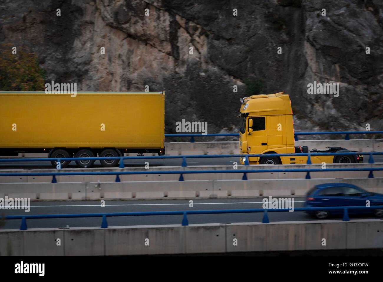 Yellow refrigerated semi-trailer with a truck of the same color behind ...