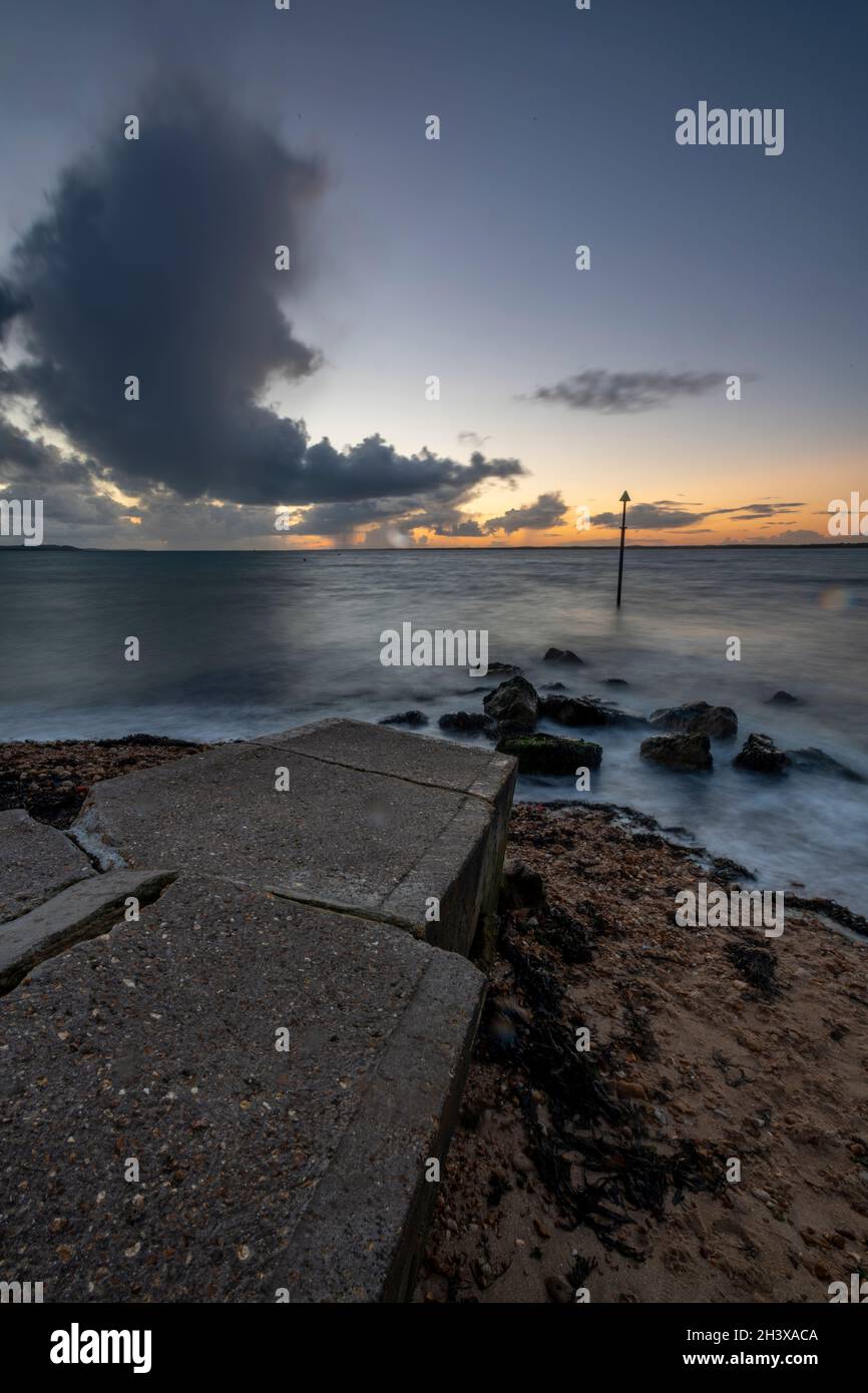 old stone jetty or pier on the coastline of the isle of wight at sunset ...