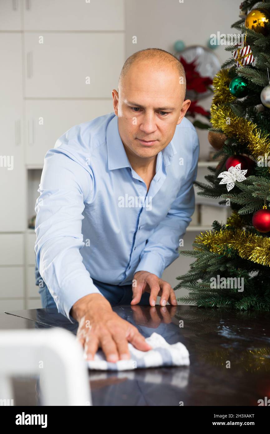 Positive man wipes the table before Christmas Stock Photo - Alamy