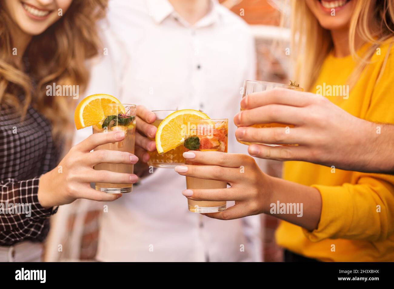 Crop happy friends drinking cocktails together Stock Photo - Alamy