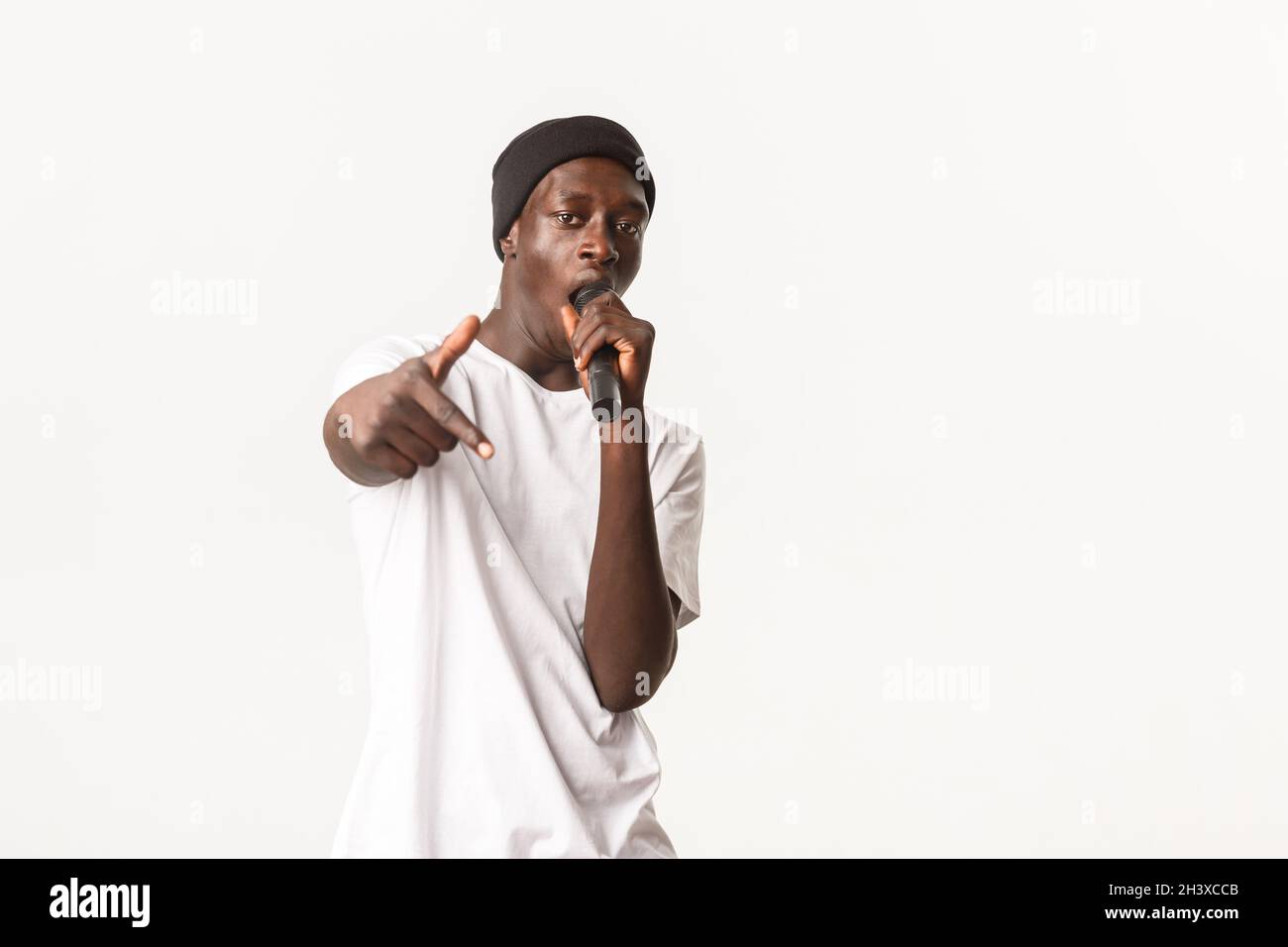 Portrait of sassy and cool Black rapper in beanie, singing into ...