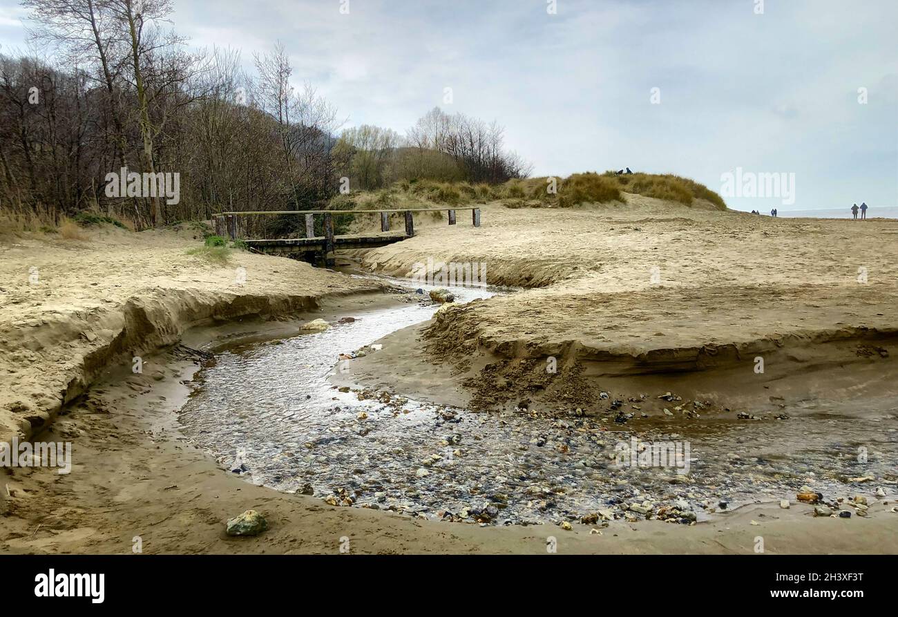 View of a beach washed by sea water, with rocks. Wet sand is drawings ...