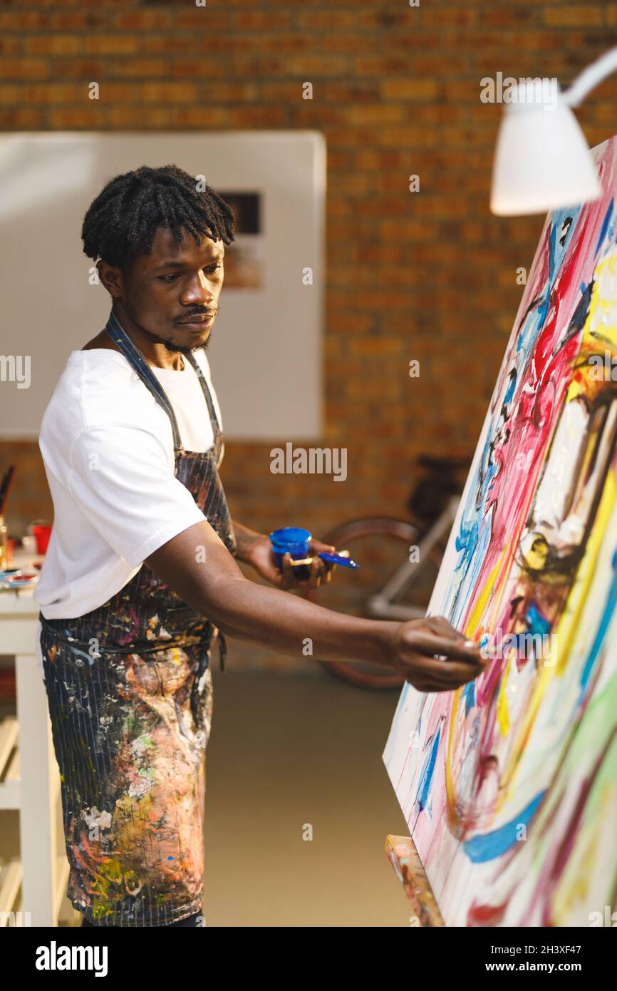 African american male painter at work painting on canvas in art studio ...