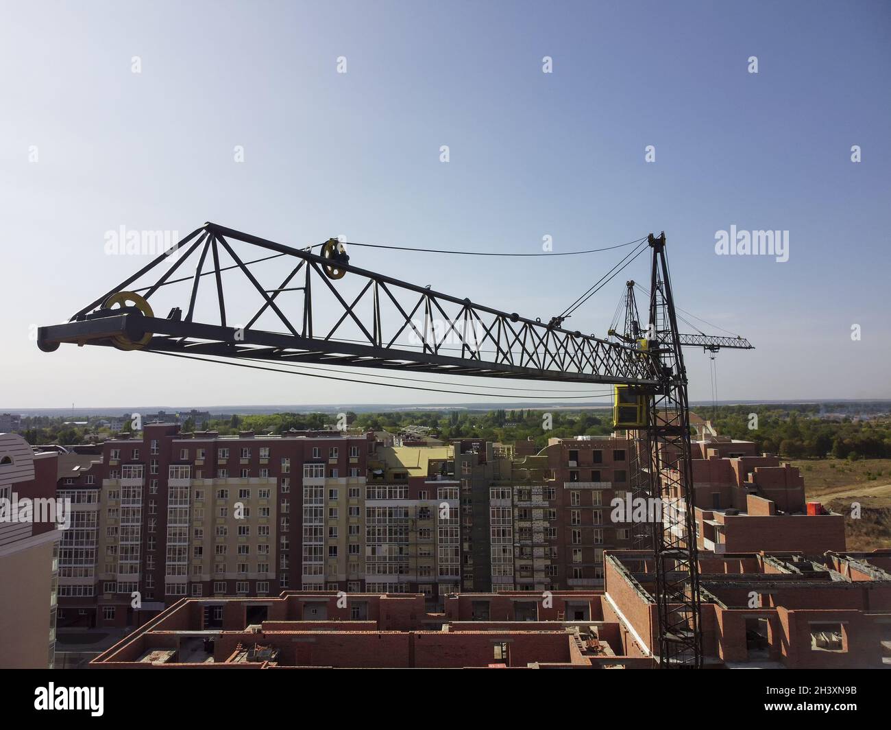 Crane over new buildings. Aerial view, cargo crane boom high in the sky ...
