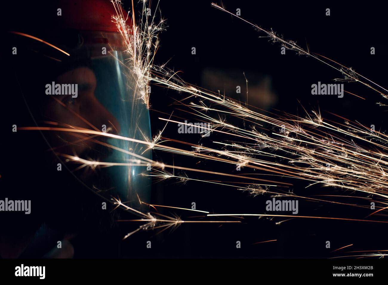 Man worker in transparent protective mask works on metal with circular ...