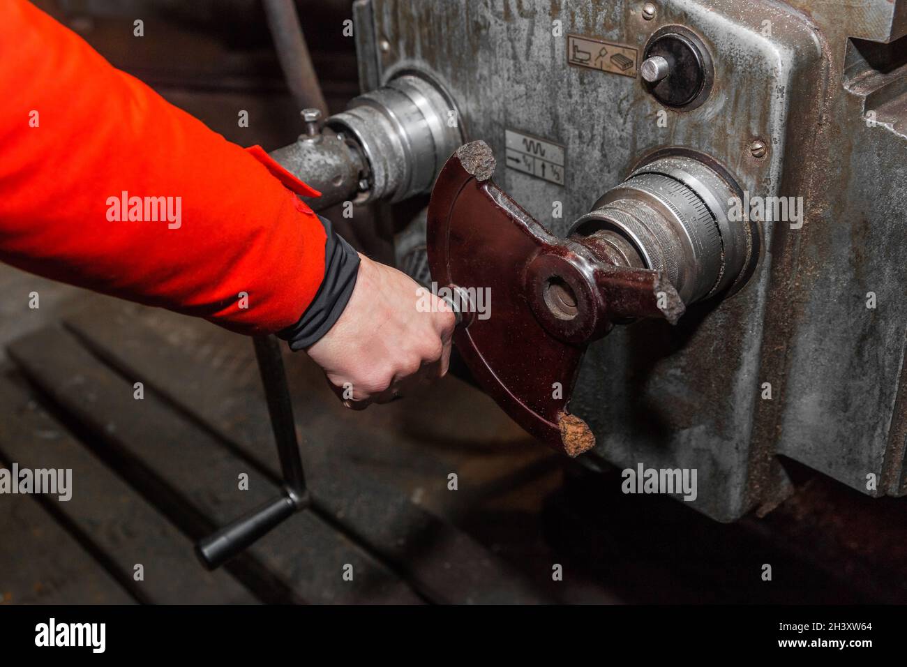 The hand of a man in a red work suit, holds on to the handle and ...