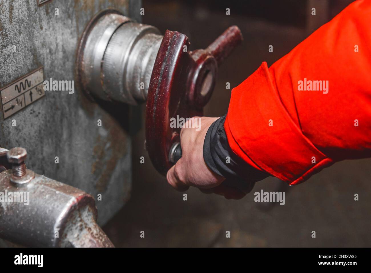The hand of a man worker in a suit controls the milling machine by the ...