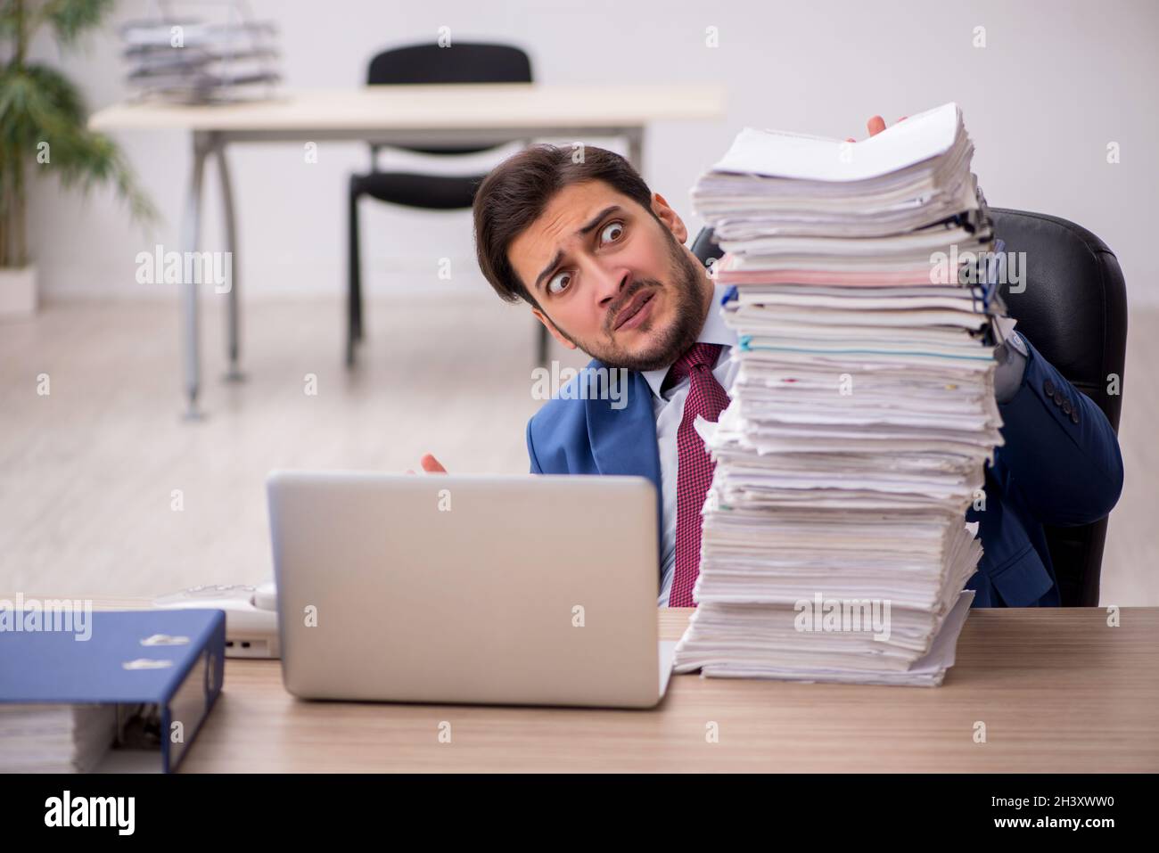 Young male employee and too much work in the office Stock Photo - Alamy