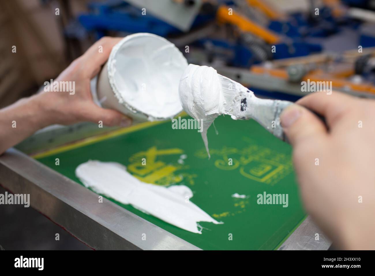 Serigraphy silk screen print process at clothes factory. Paint ...