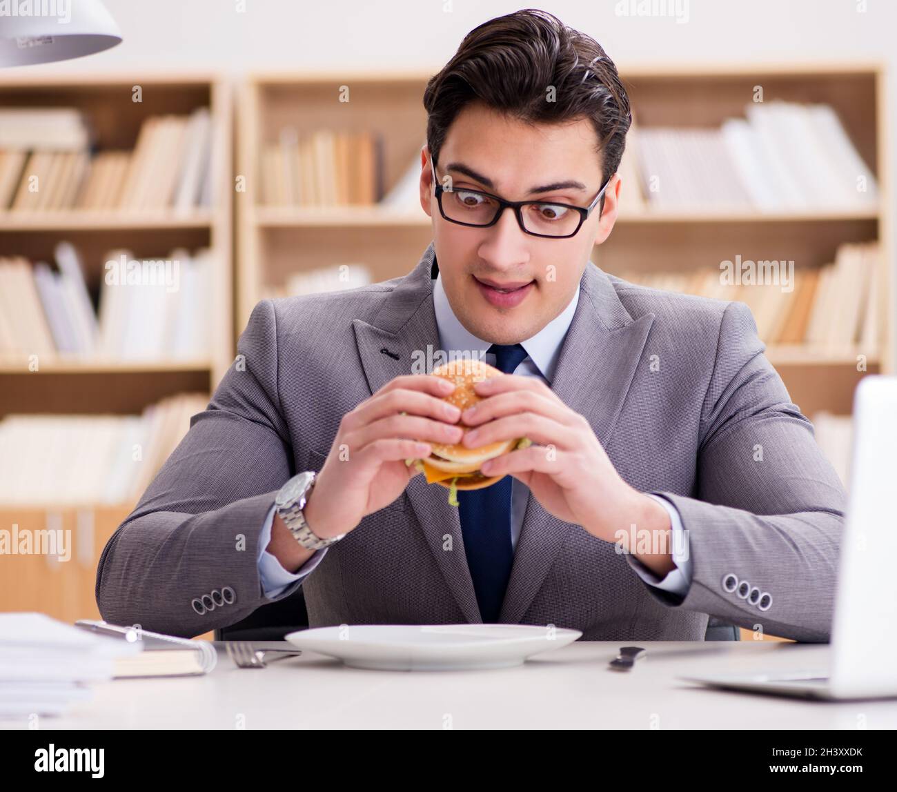 Hungry funny businessman eating junk food sandwich Stock Photo - Alamy
