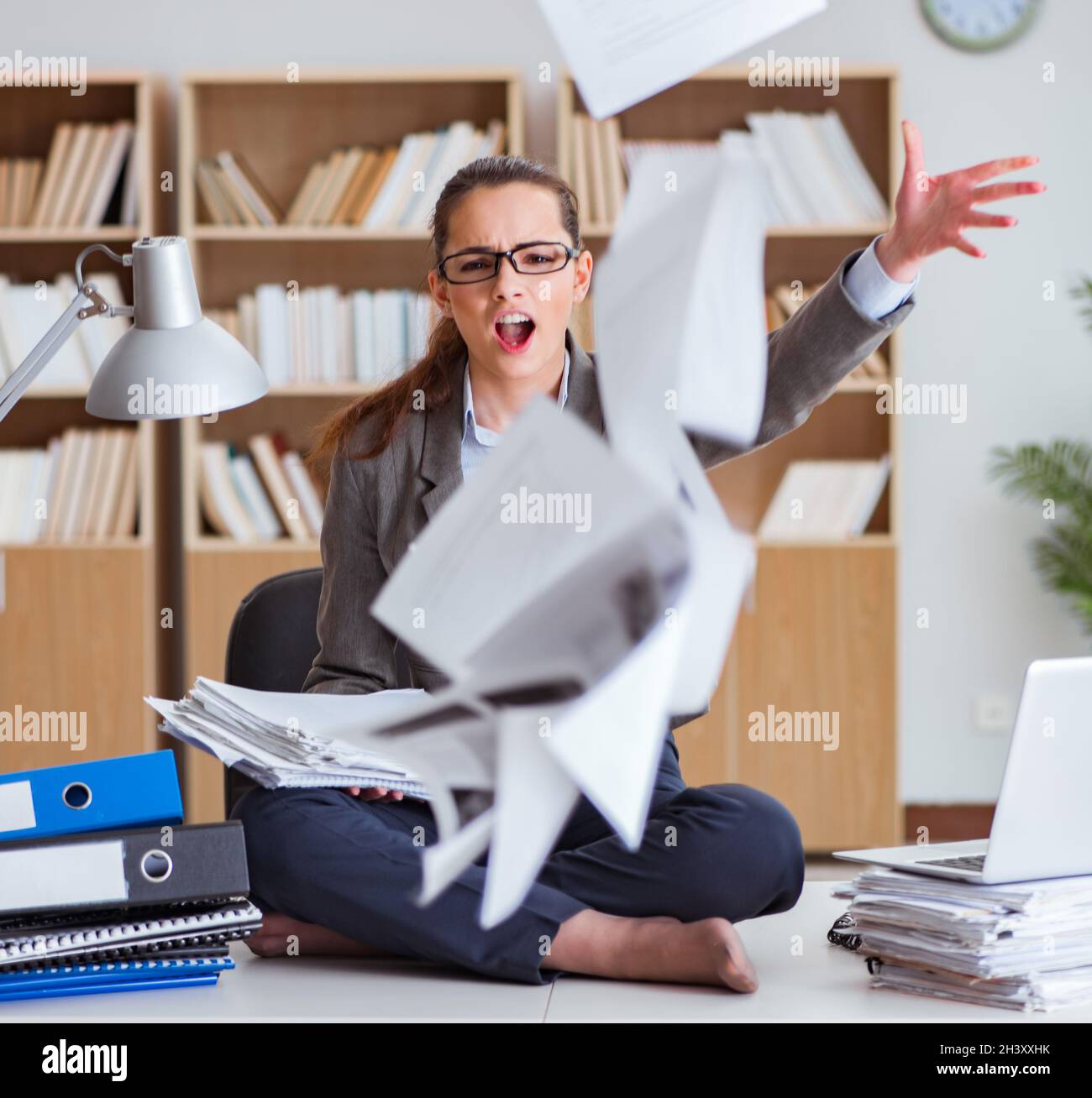 Busy angry businesswoman sitting on the desk in office Stock Photo - Alamy