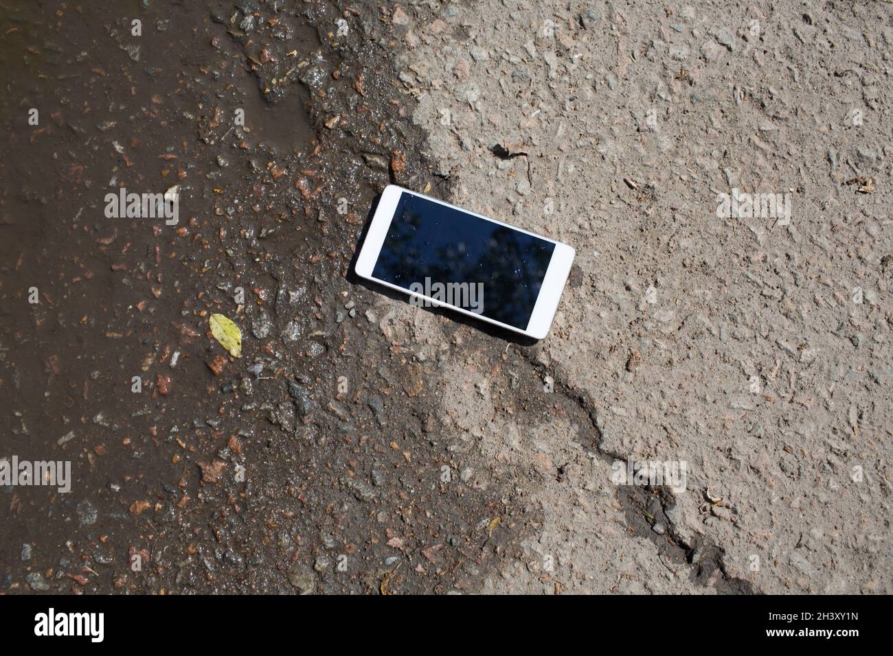 Mobile phone lying on pavement in puddle Stock Photo - Alamy